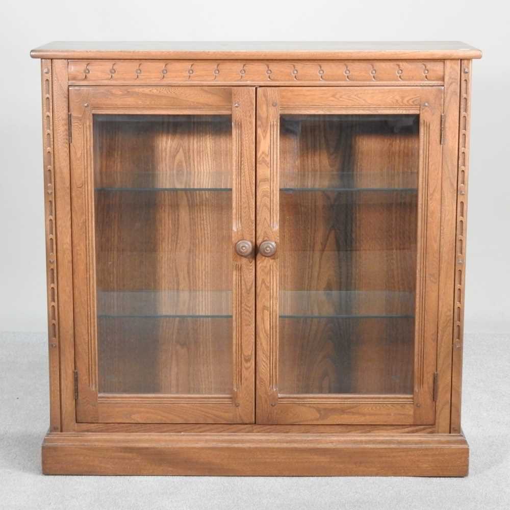 Lot 387 - A 1970s Ercol elm glazed dwarf bookcase, on